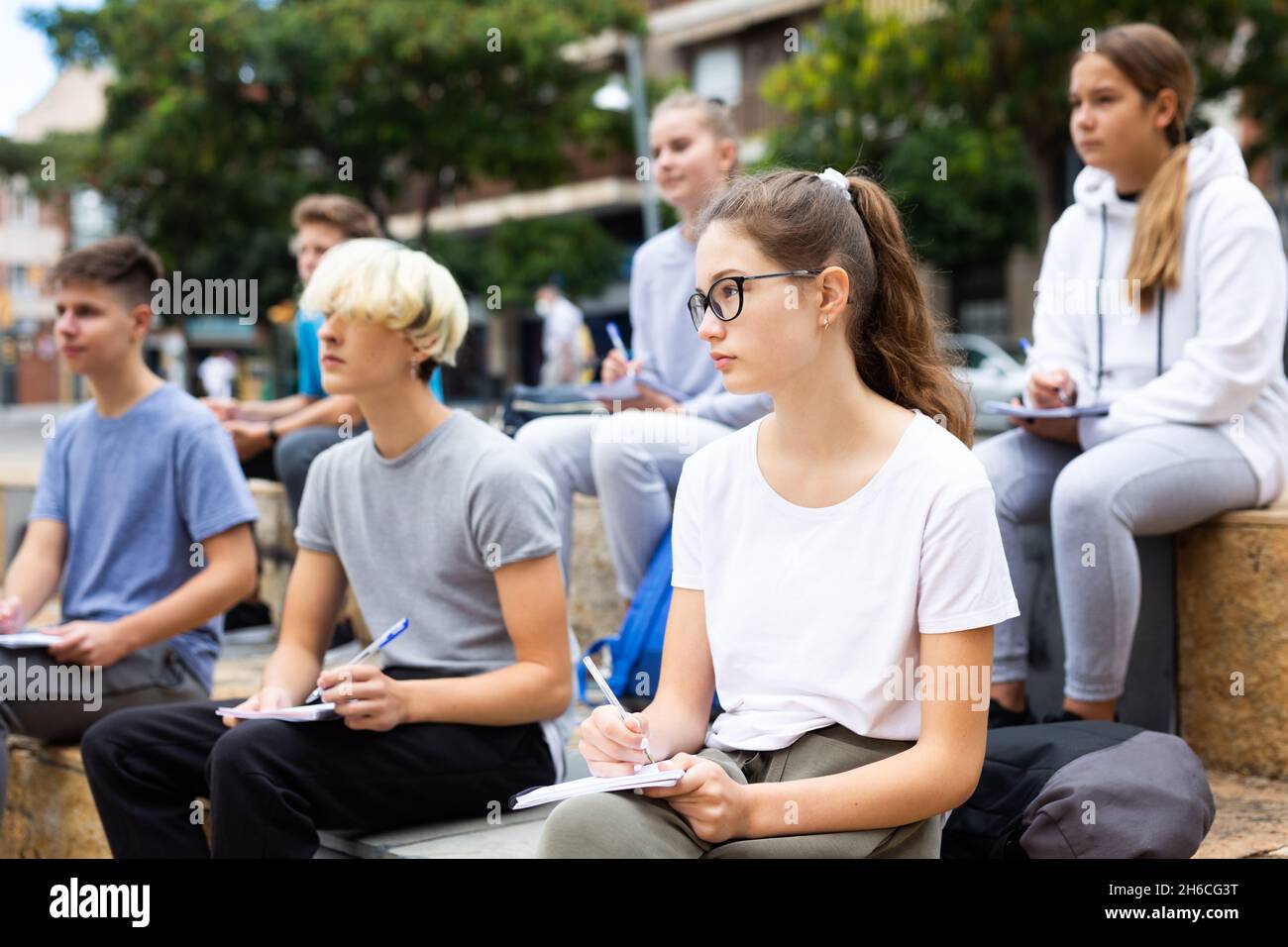 Students record lecture while sitting on a stone street parapet Stock ...