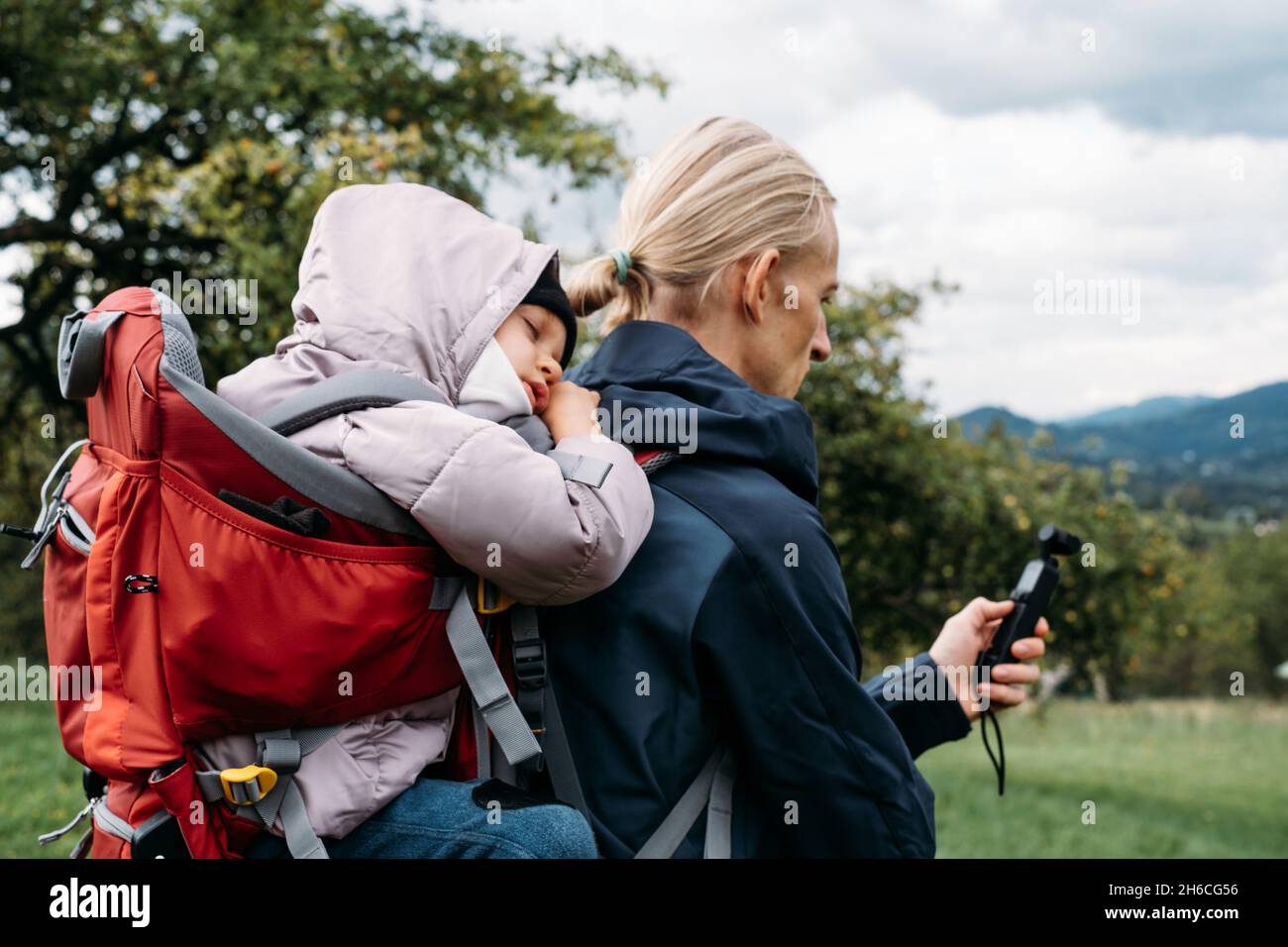 Father taking pictures while hiking with child in backpack. Vlogger man ...
