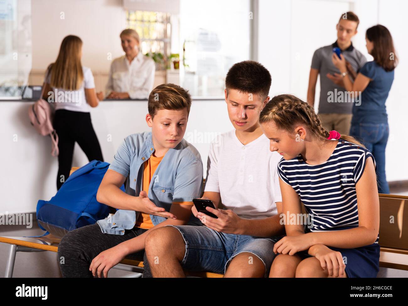 Girl and boys using phones, have rest between lessons Stock Photo - Alamy