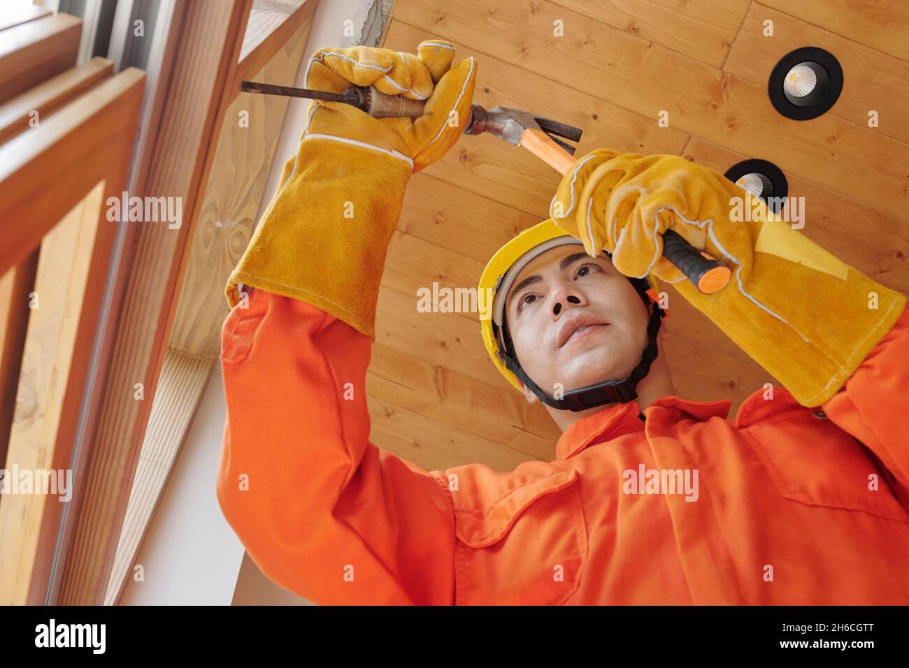 Concentrated young Vietnamese builder using hammer and chisel when ...