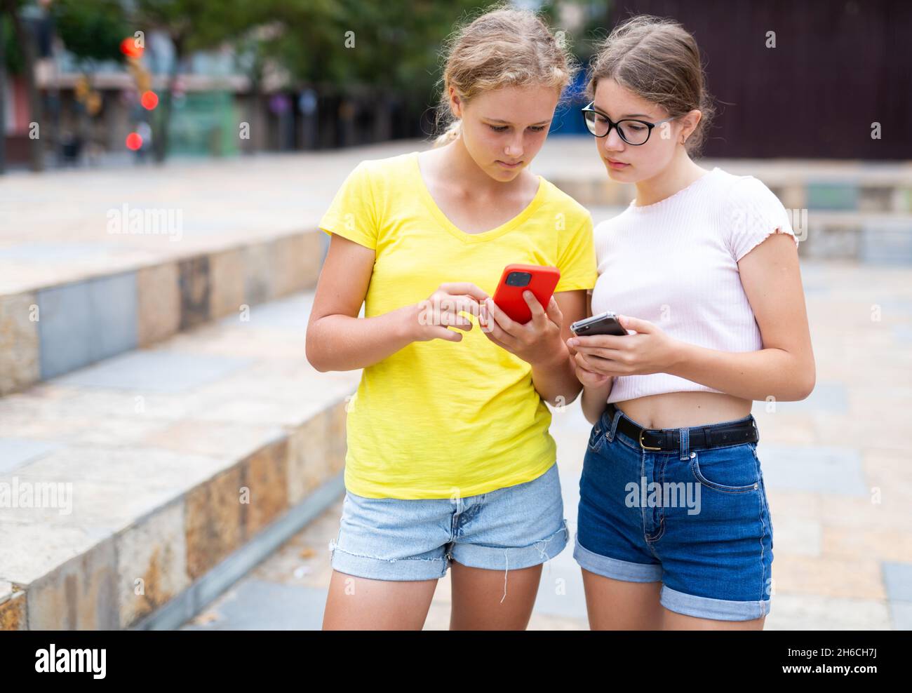 Two teenagers chatting on their smartphone Stock Photo - Alamy