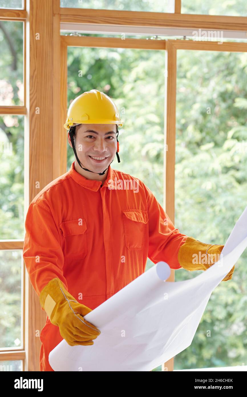 Portrait of positive foreman with building plan in hands smiling and ...
