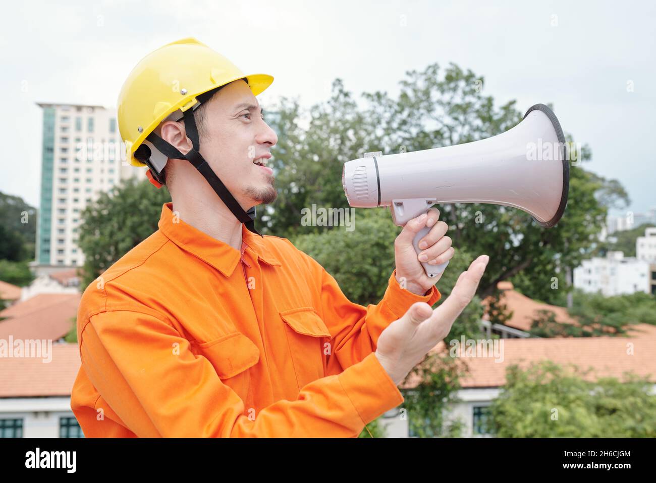 Portrait of construction site worker with loudspeaker standing on ...