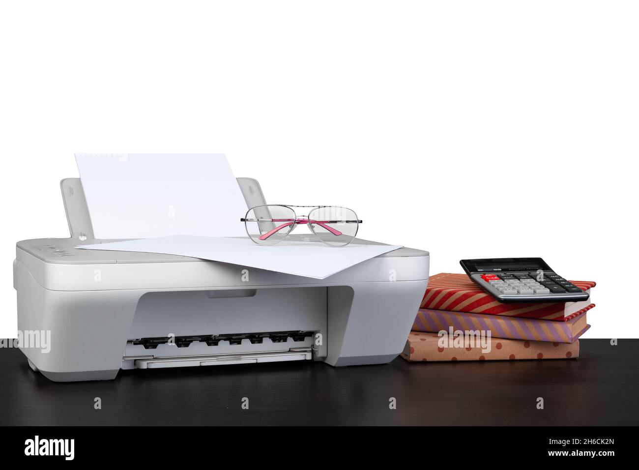 Printer and stack of books on black table against white background ...