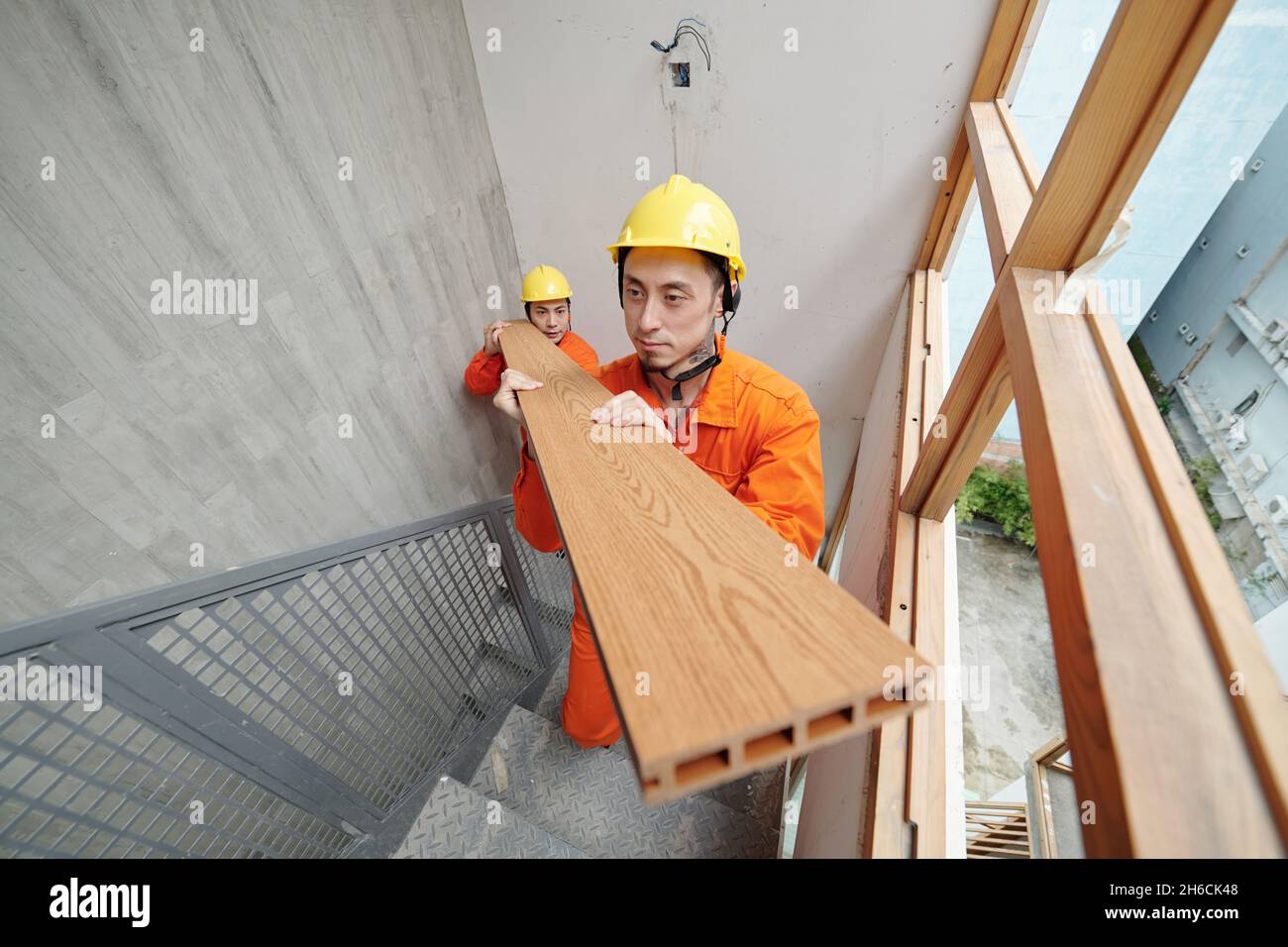 Serious construction workers carrying building materials to the upper ...