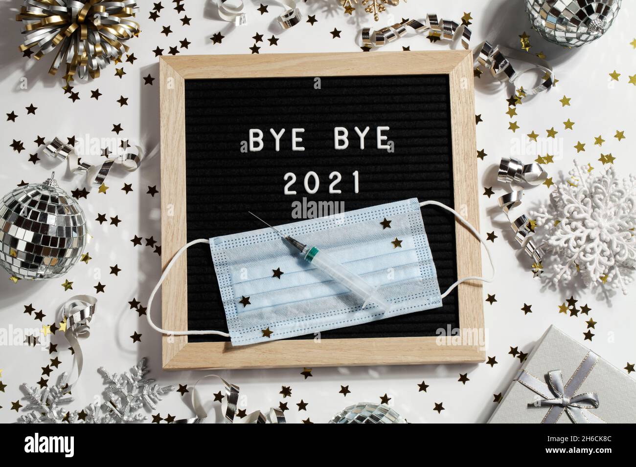 black letter board with text BYE BYE 2021 with decoration, syringe and ...