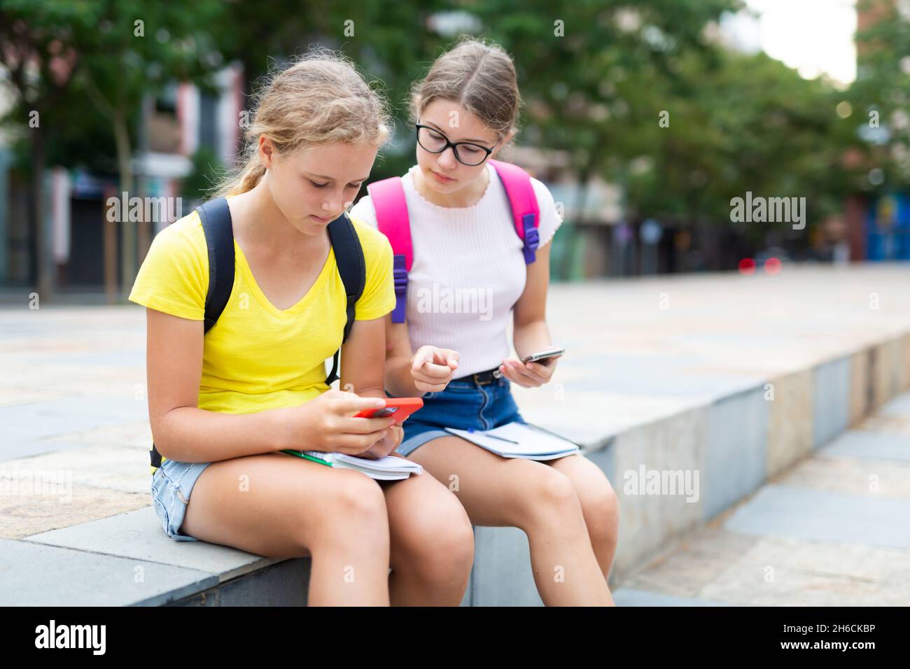 Teen girls teach lessons using smartphones outdoors Stock Photo - Alamy