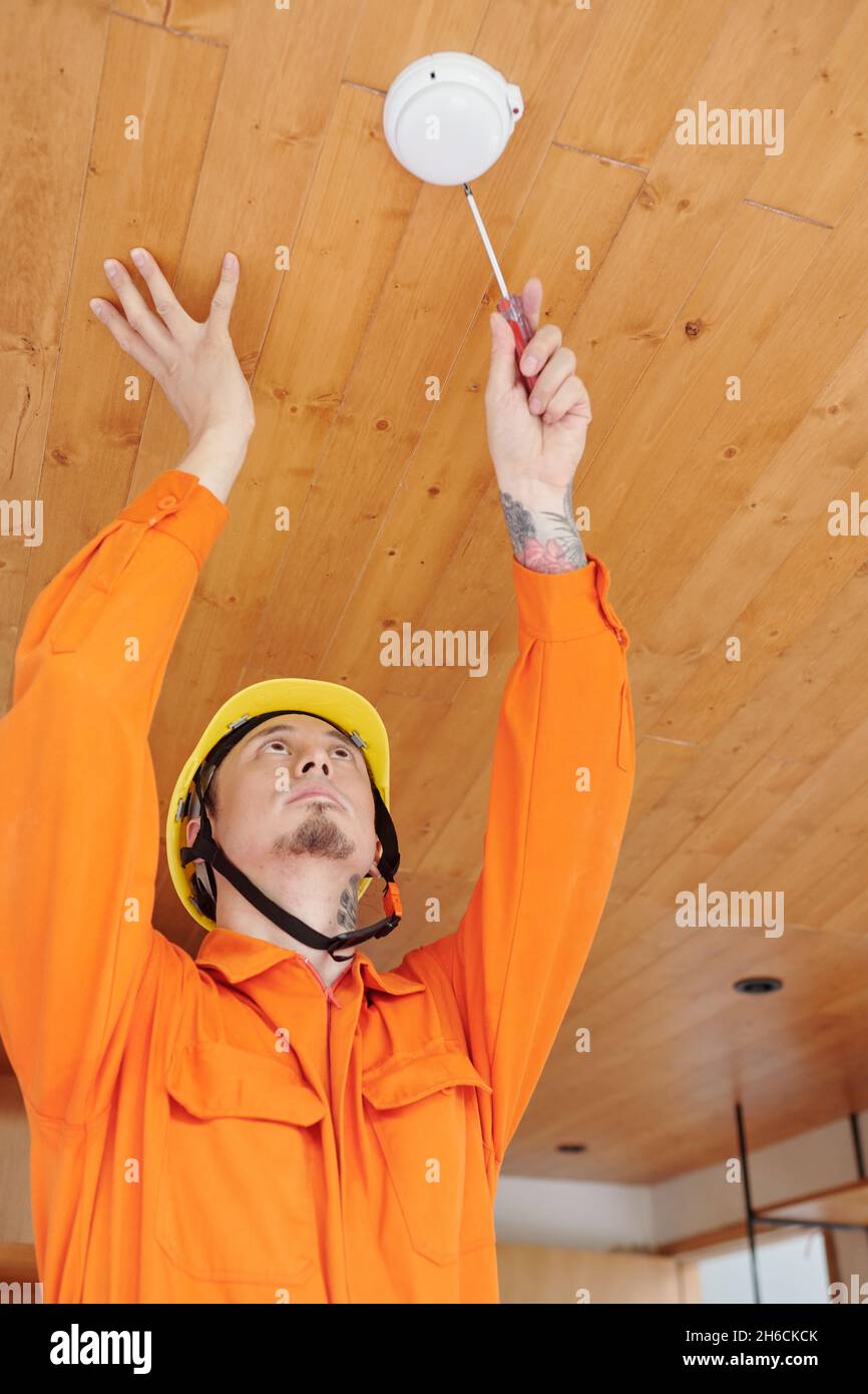 Technician with screwdriver installing security system sensor on ...