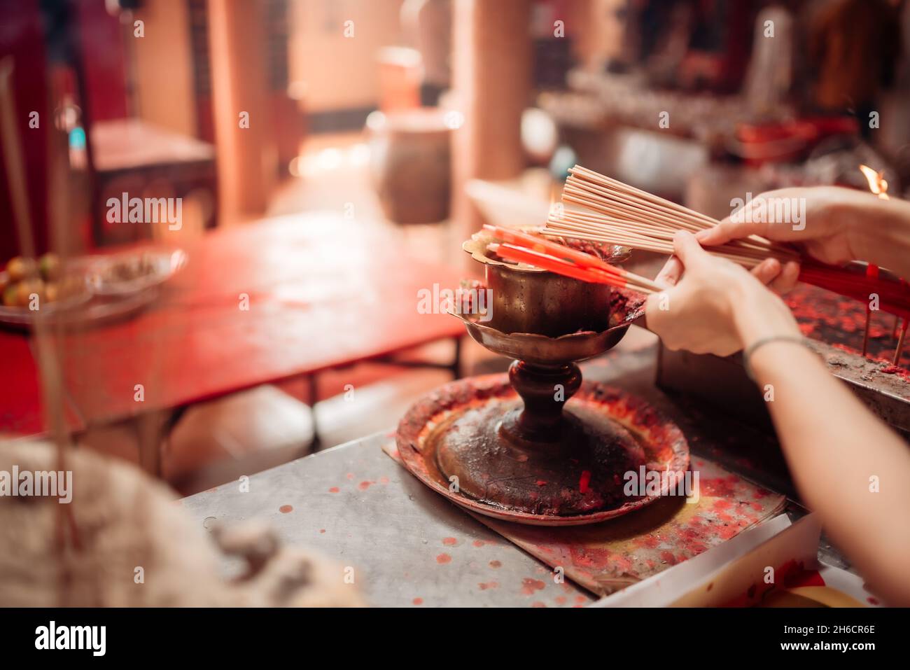 A hand holding incense and lighting it with candle Stock Photo - Alamy