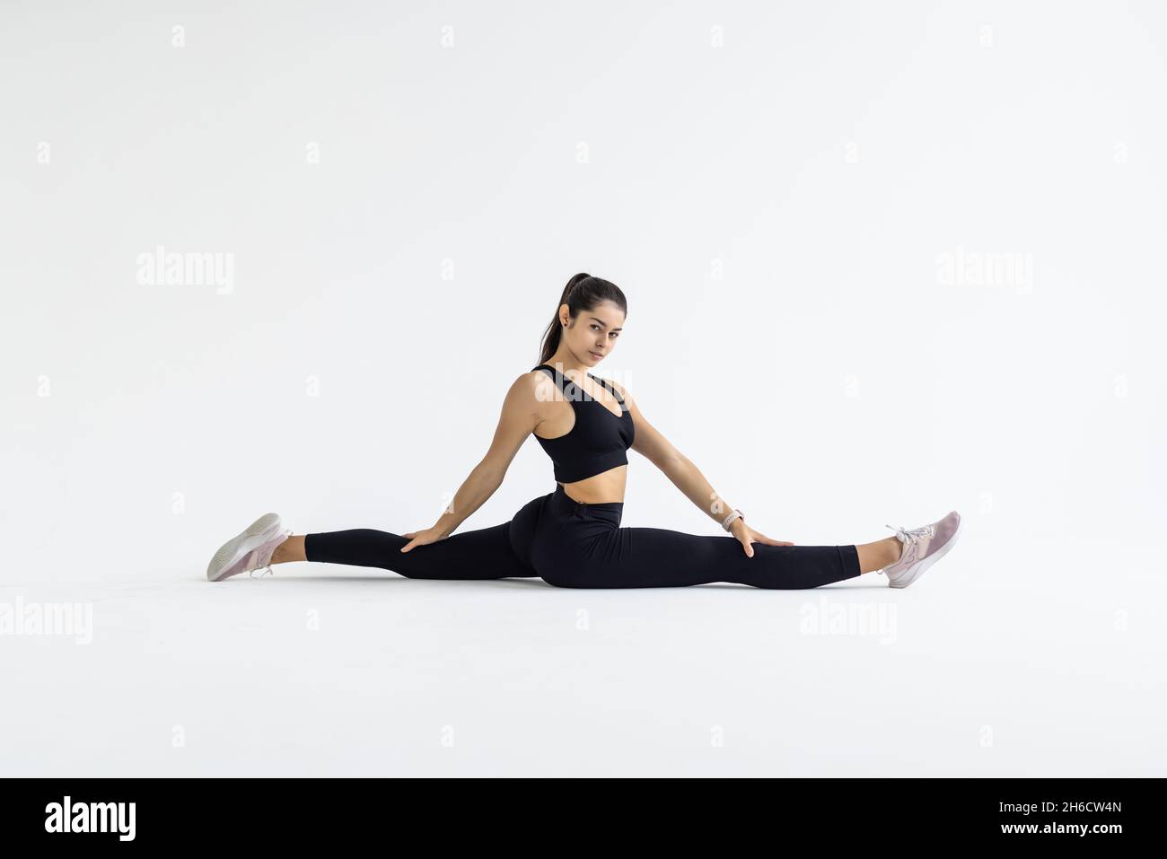 Young healthy girl doing stretching exercises over white background ...