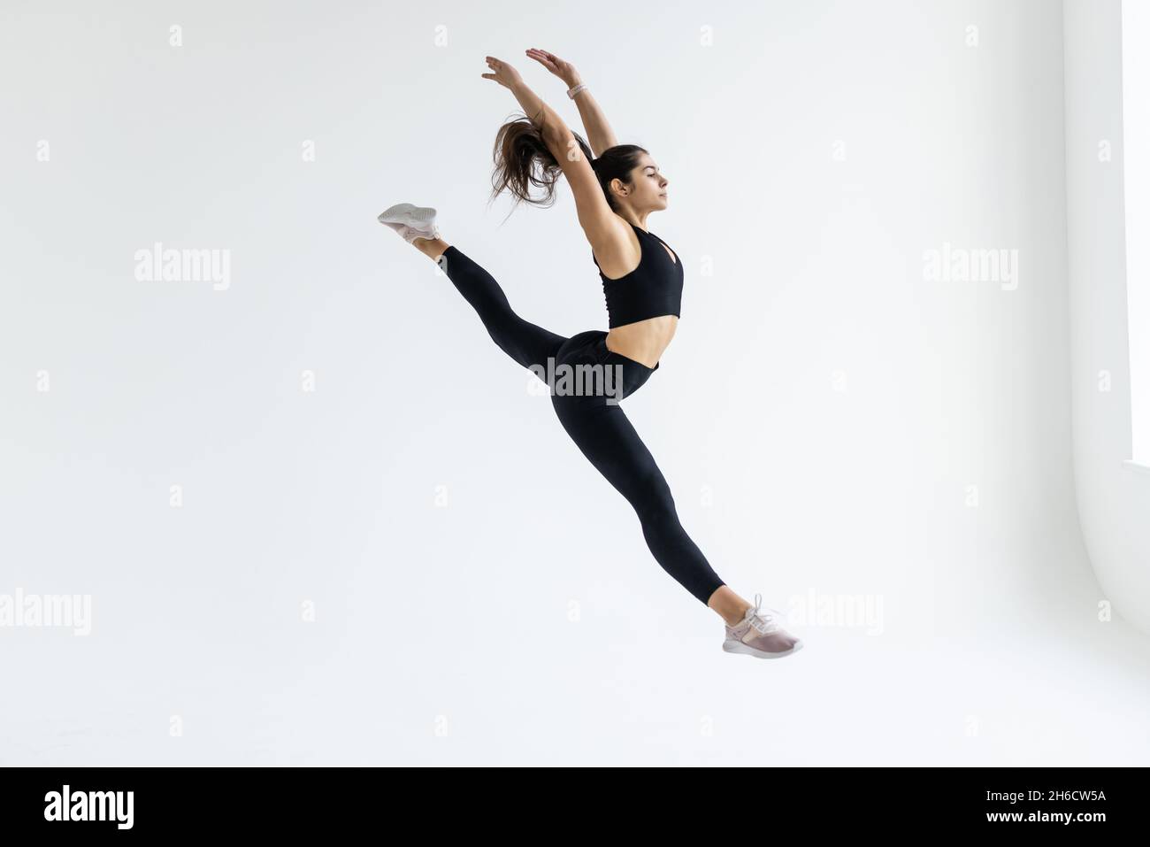 Side view of a sporty young woman jumping isolated on white background ...