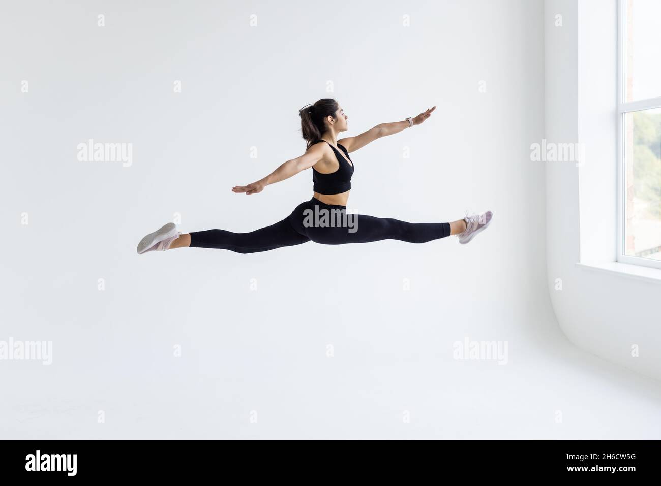 Side view of a sporty young woman jumping isolated on white background ...