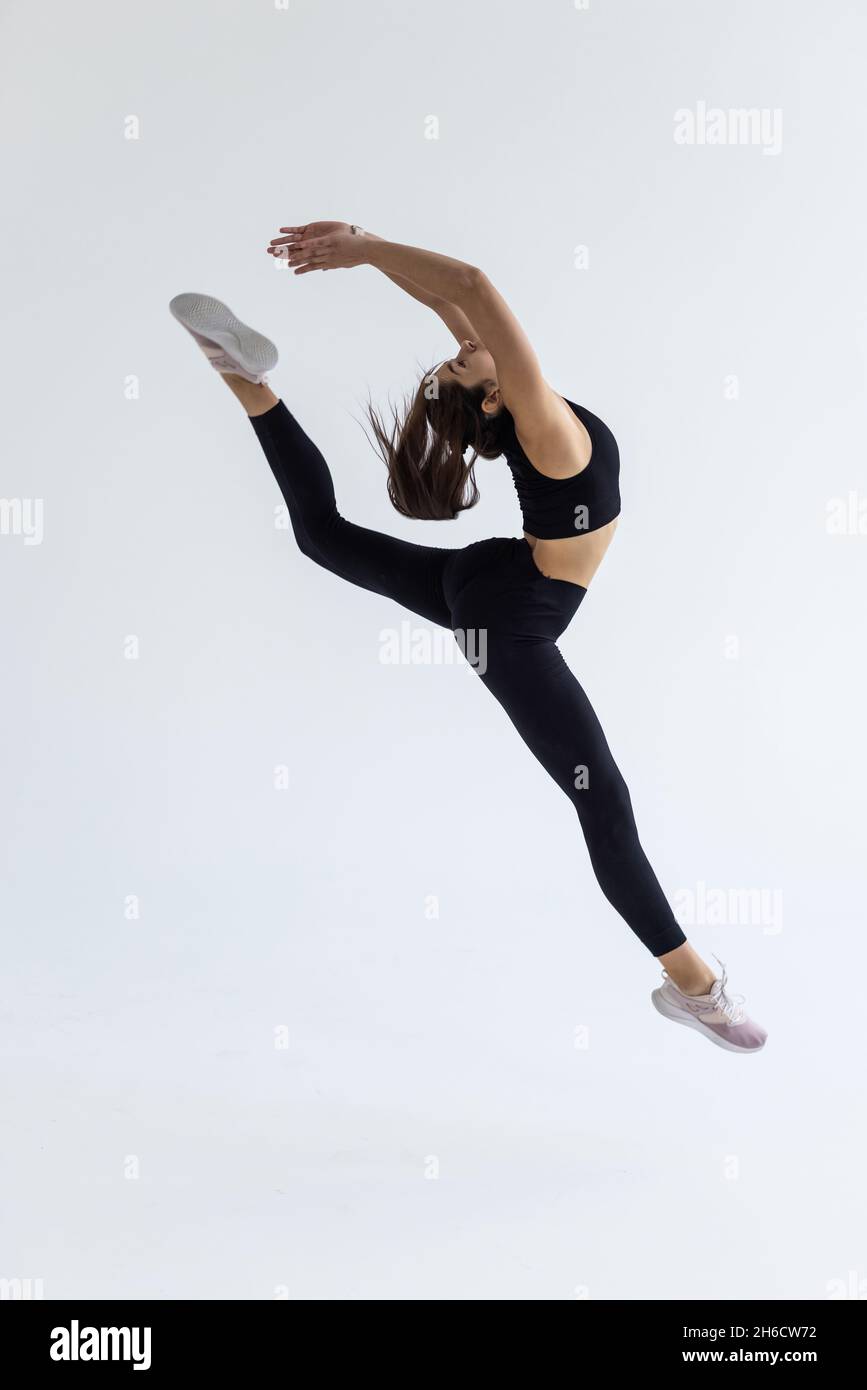 Side view of a sporty young woman jumping isolated on white background ...
