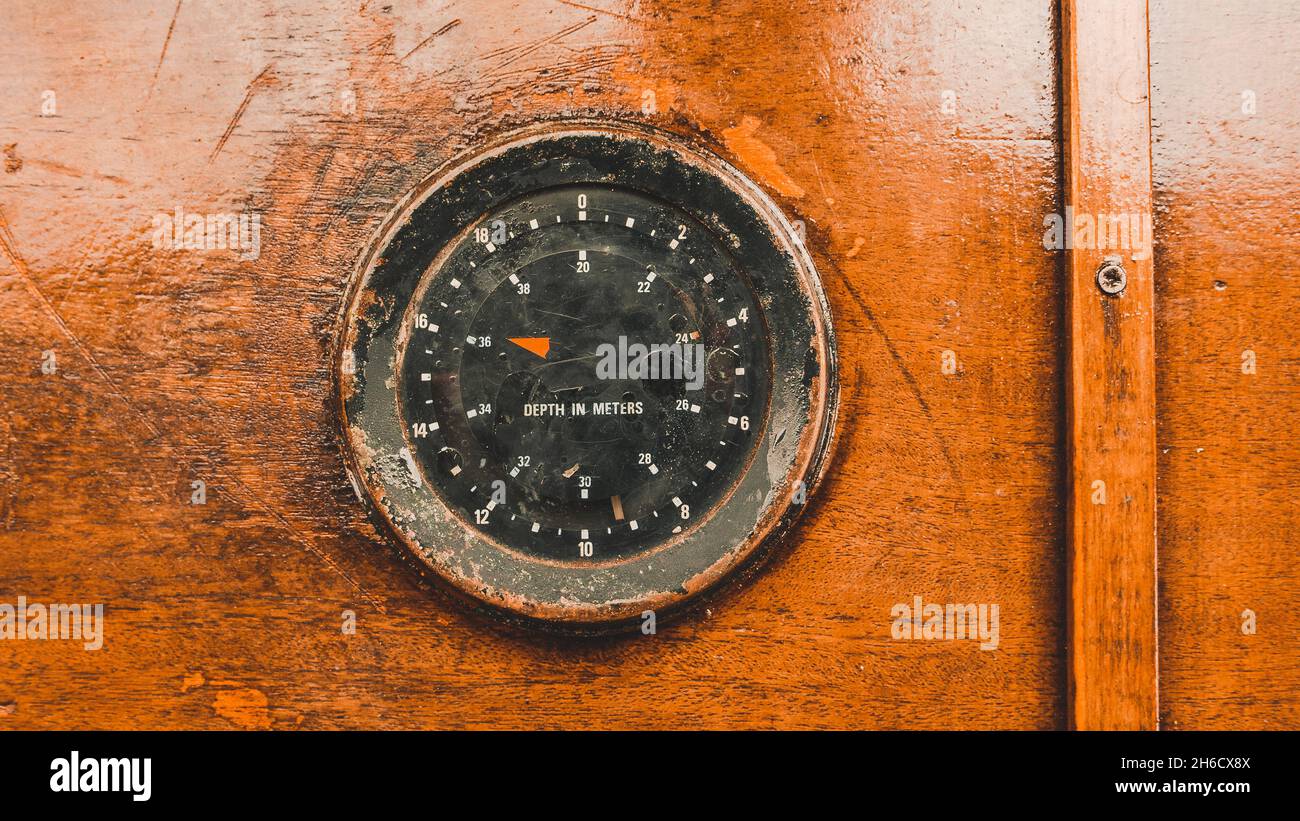 Old nautical depth meter on boat dashboard with worn wooden surface ...