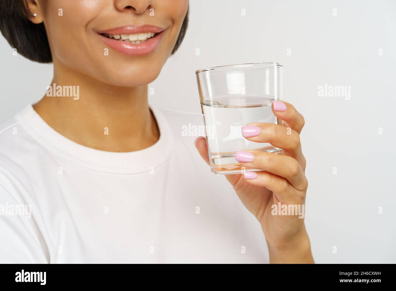 Smiling african woman hold glass of still water. Water balance and caring for skin and body ...