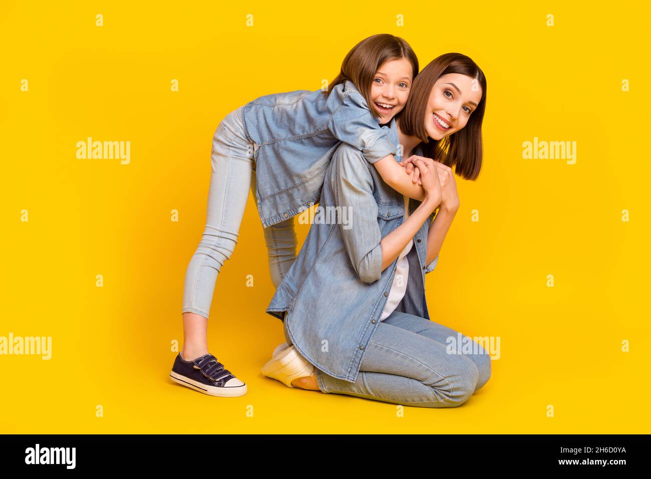 Photo of two relaxed fooling sisters wear jeans shirts smiling sitting ...