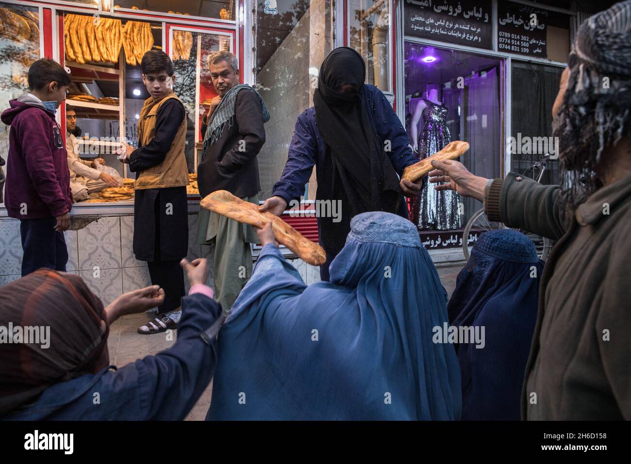 EDITORIAL USE ONLY - Burqa-clad Afghan women and men wait for donations ...