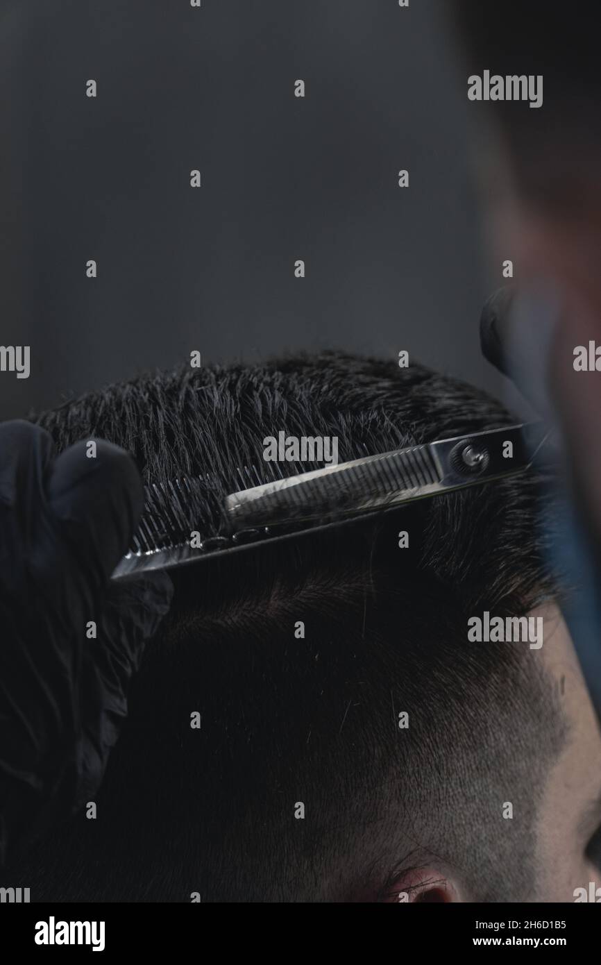 Vertical shot of a barber's hands cutting a client's hair with scissors ...