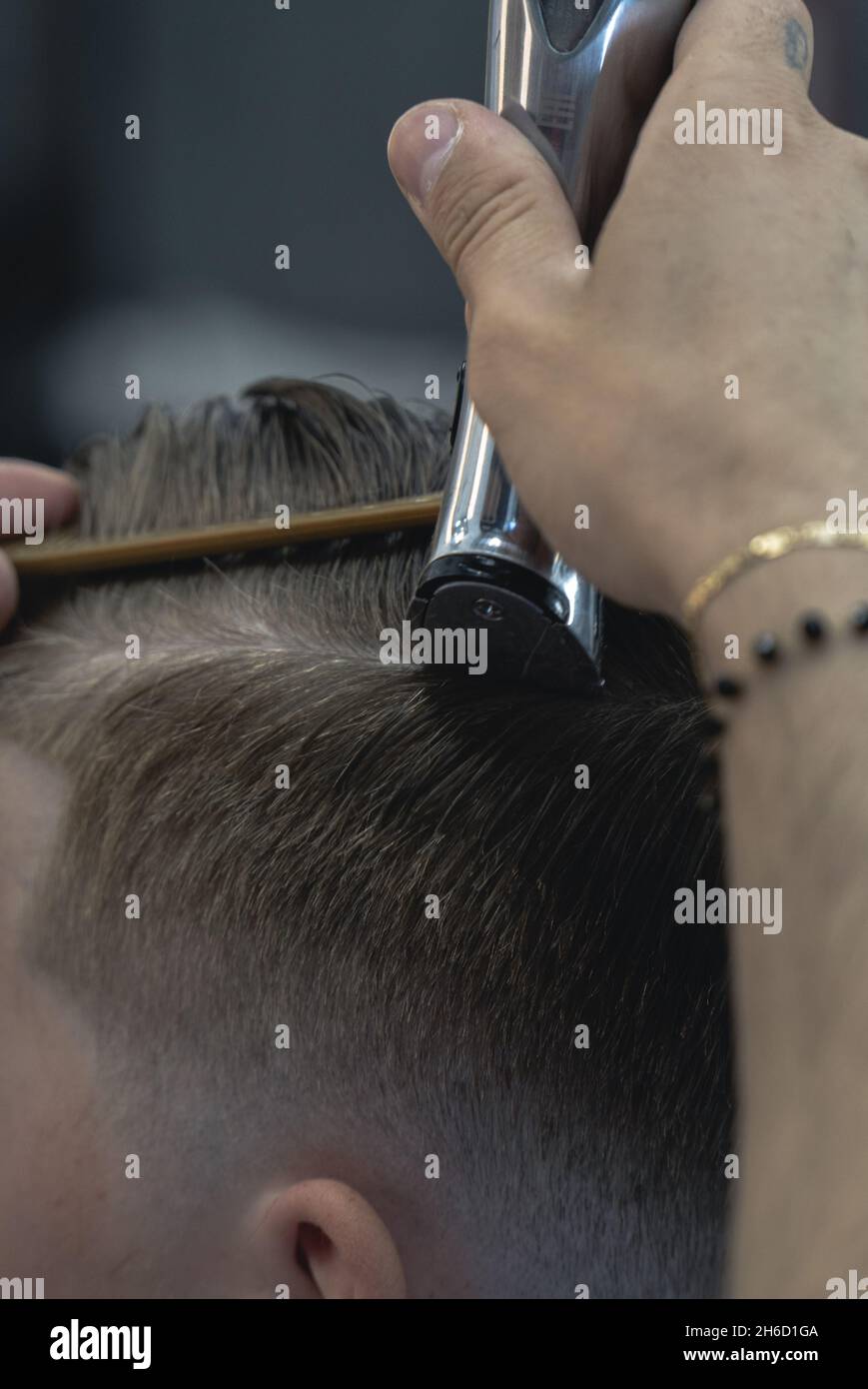 Vertical shot of a barber's hands cutting a client's hair with a ...