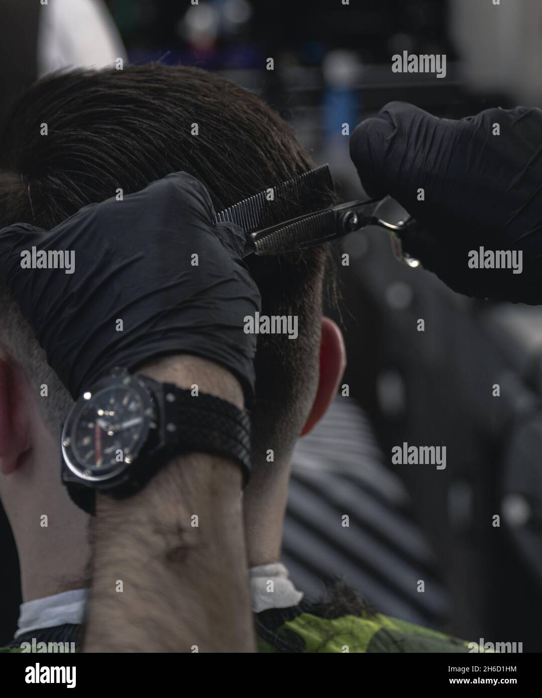 Barber's hands cutting a client's hair with scissors in a barbershop ...