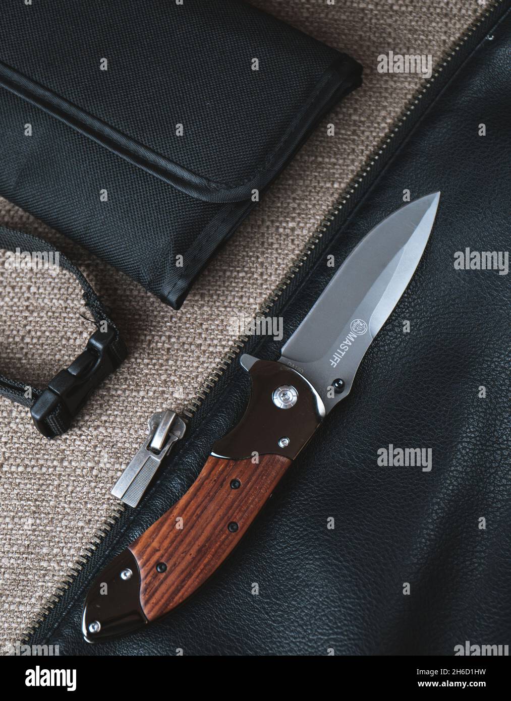 Vertical shot of folding knife with leather and brown wooden handle ...