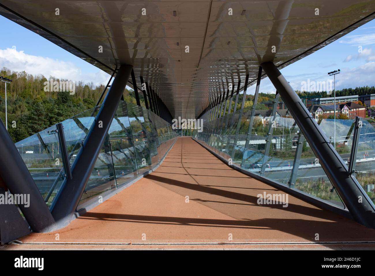 Modern footbridge, with glass safety panels, crossing a road leading to ...