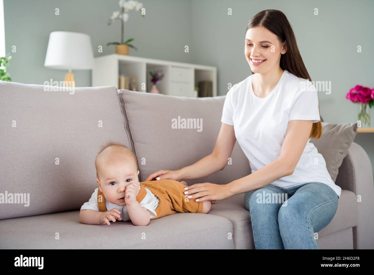 Photo of cheerful dreamy babysitter mom play little son sit comfy sofa ...
