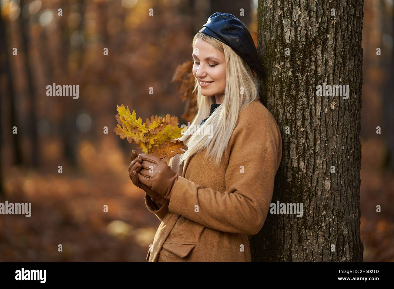 Autumnal candid portrait of a blonde young woman in coat and cap in the ...