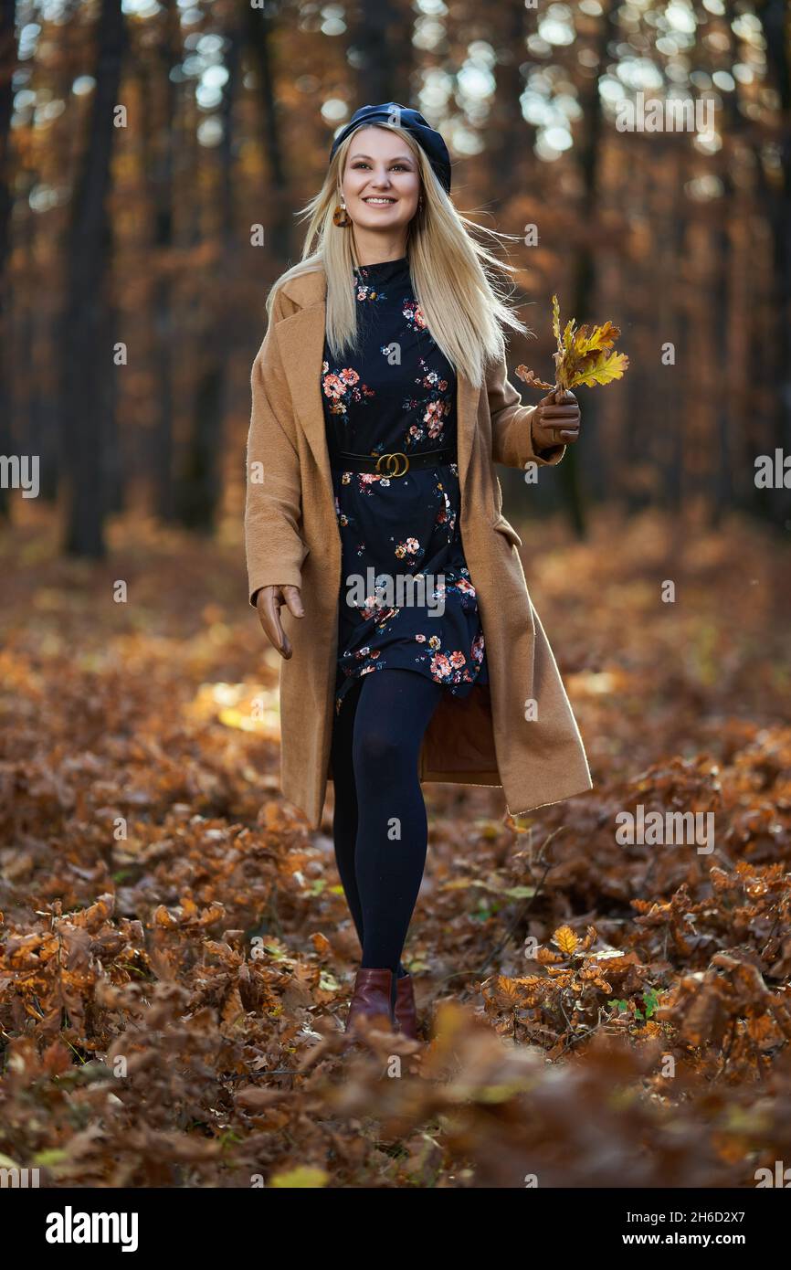 Autumnal candid portrait of a blonde young woman in coat and cap in the ...
