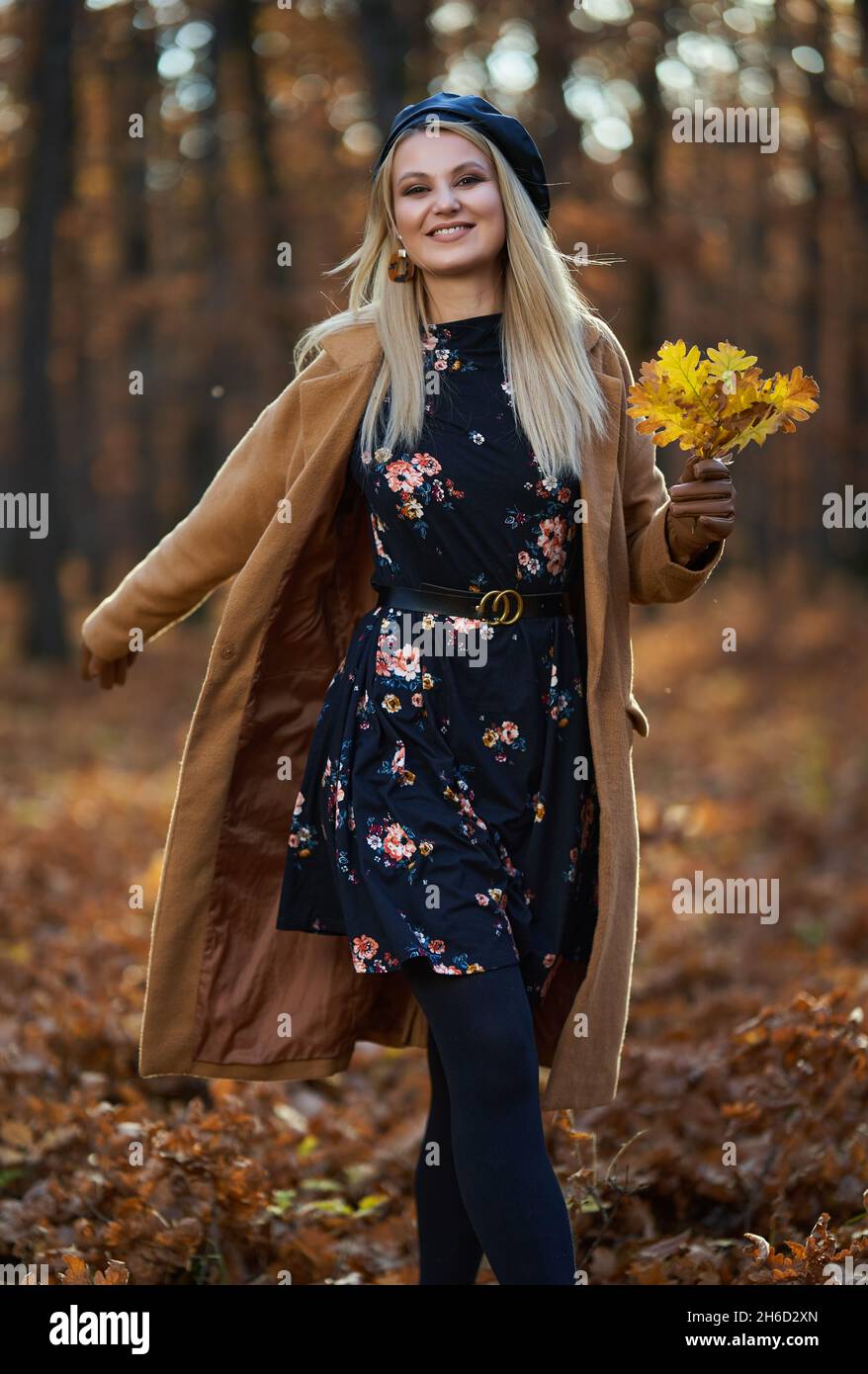 Autumnal candid portrait of a blonde young woman in coat and cap in the ...