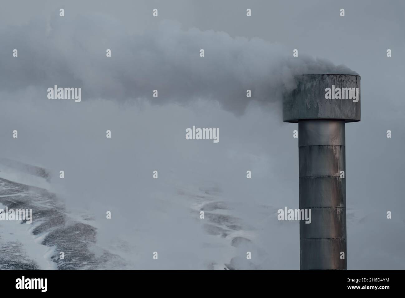Smokestack with Smoke column and snow covered mountains Stock Photo - Alamy