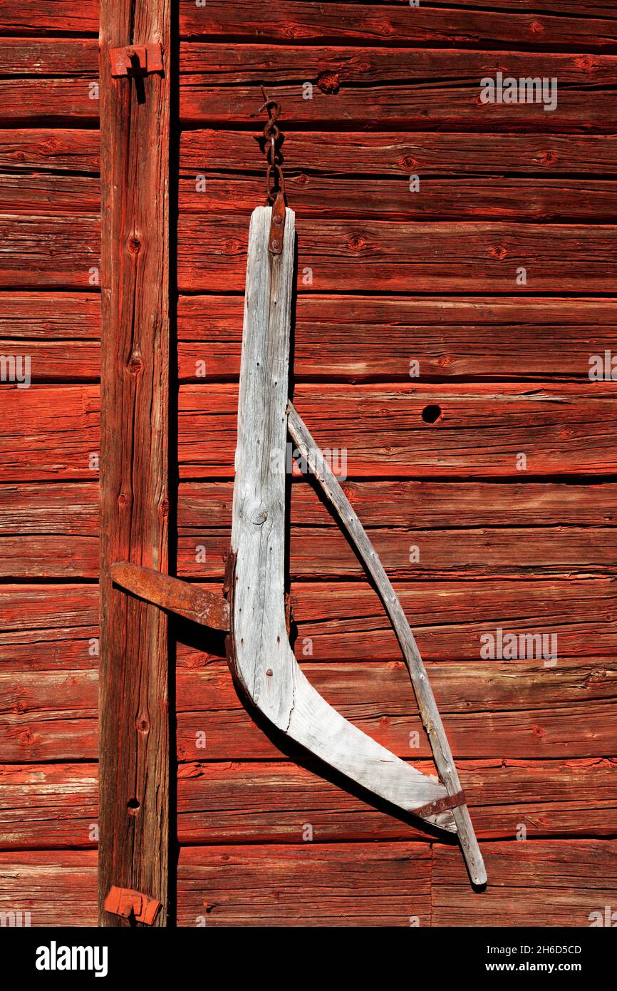 a very old agricultural tool made of wood hanging on a red barn Stock ...