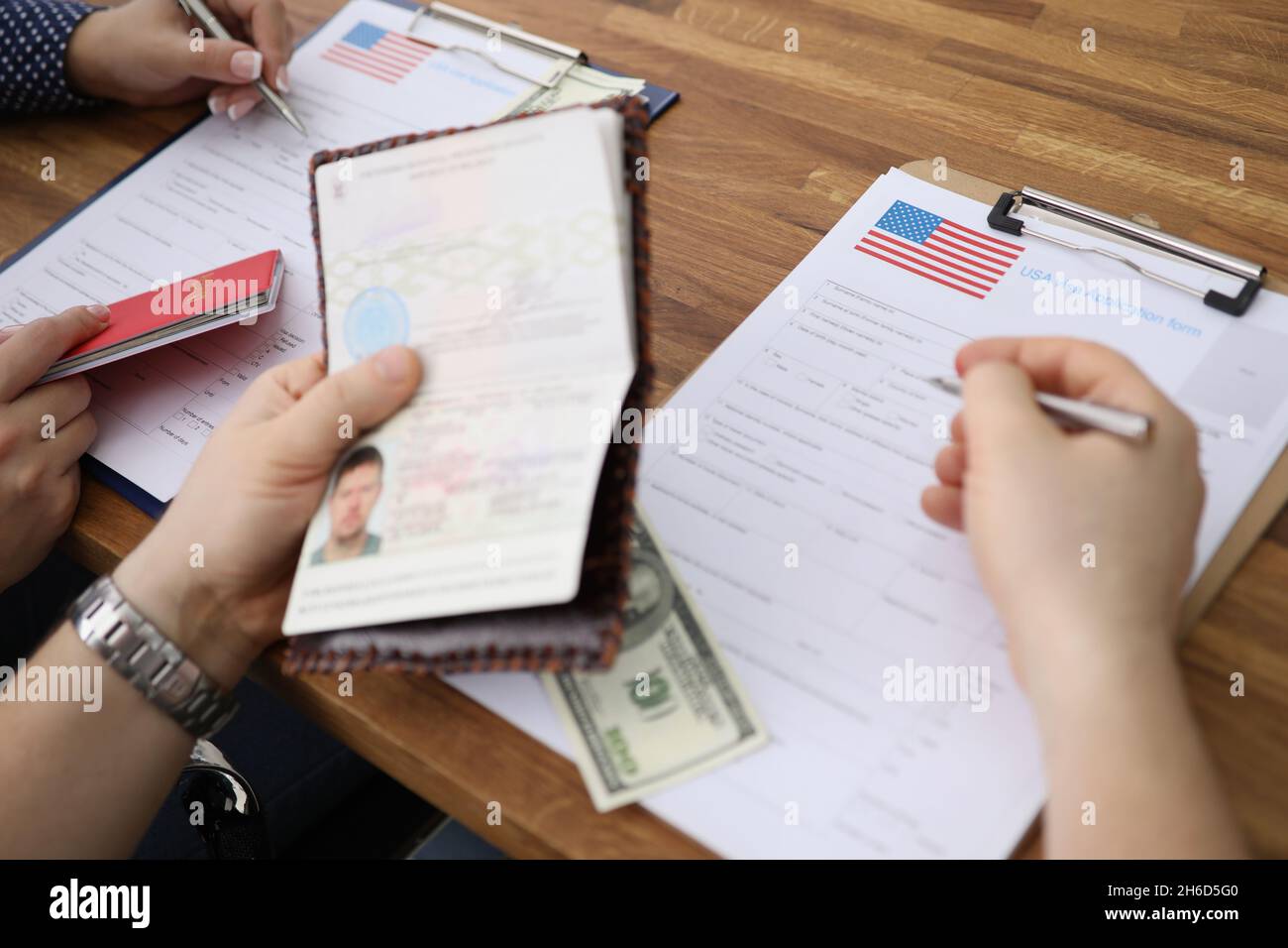 People filling visa application forms with personal passports at ...
