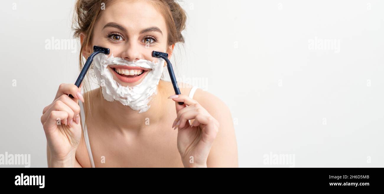 Beautiful young caucasian woman shaving her face by razor on white ...