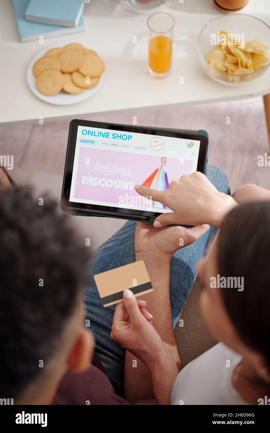 Young people with digital tablet eating snacks and shopping online ...