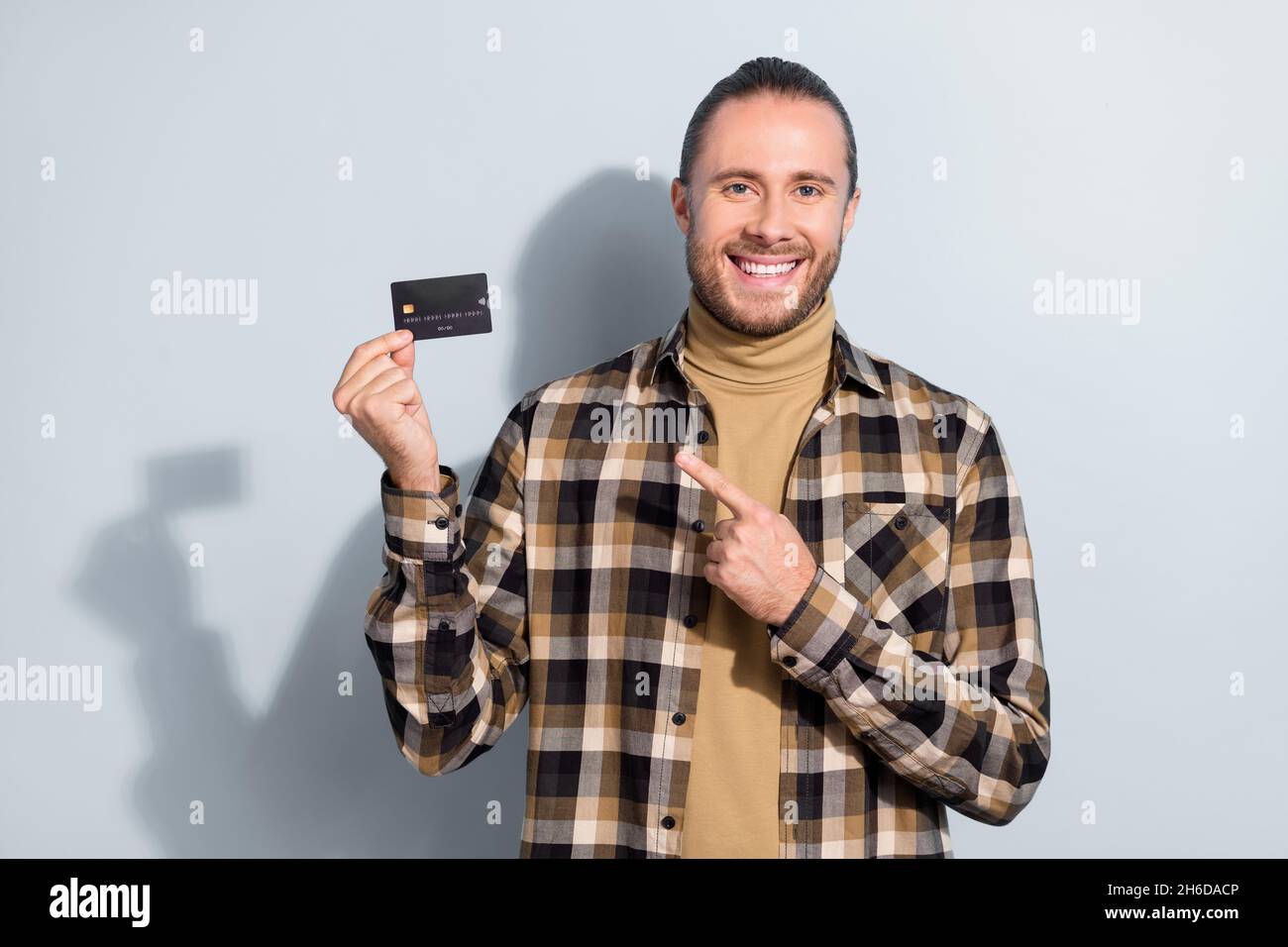 Photo of young guy hold bank card indicate finger debit card advertise ...