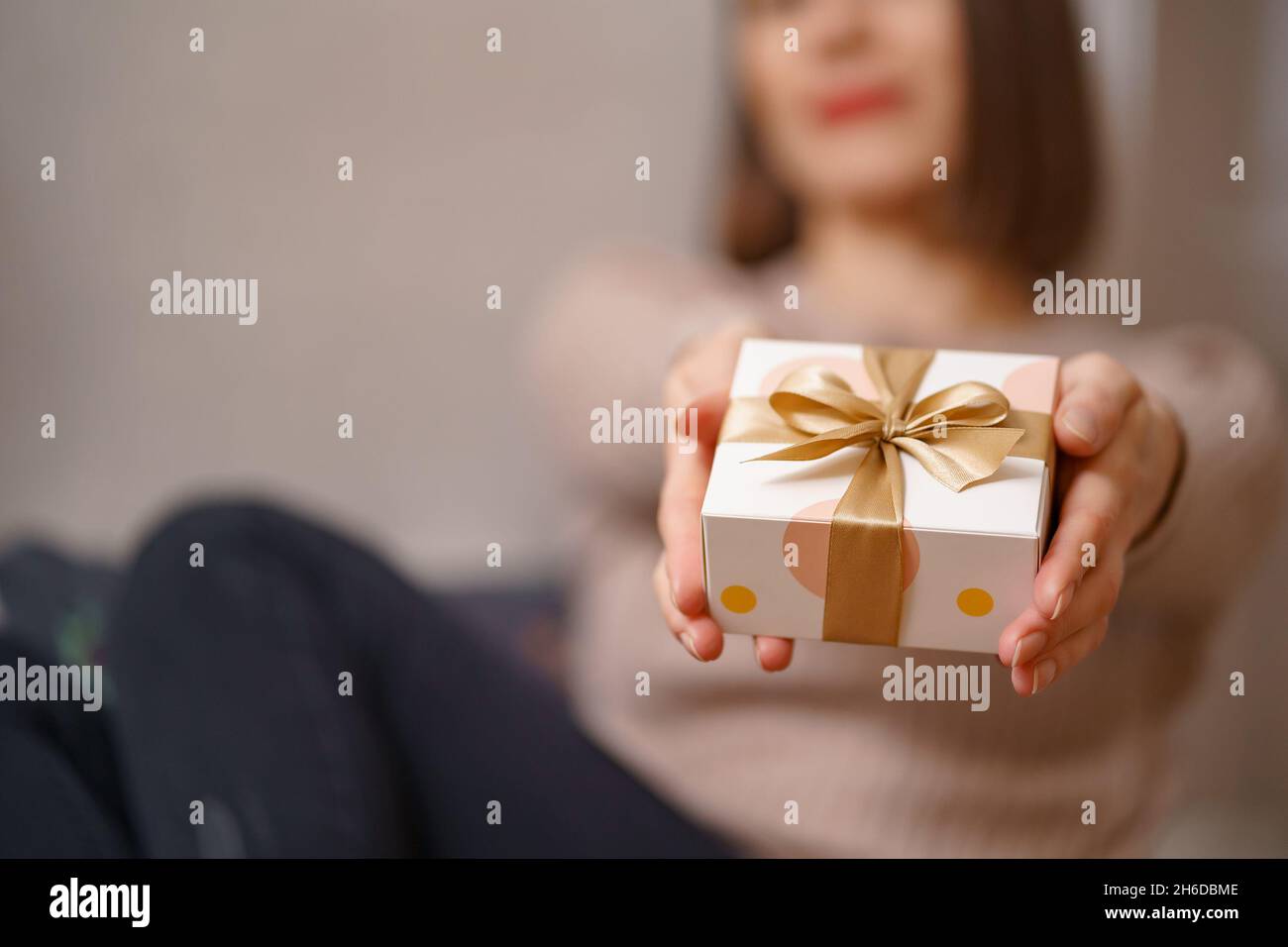 Woman hands holding wrapped white box with golden bow, focus on box ...