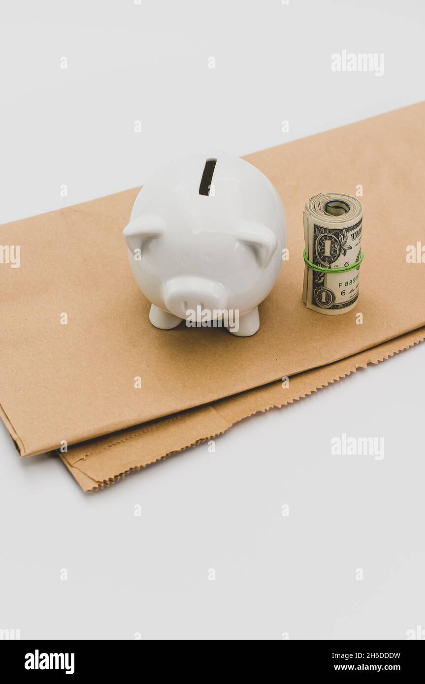 banknotes and white still bank on a folded brown paper bag on a white ...