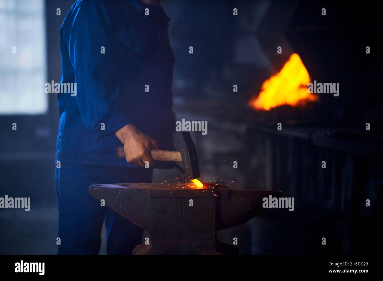 Close up of blacksmith hands hitting with hammer on glowing hot metal ...