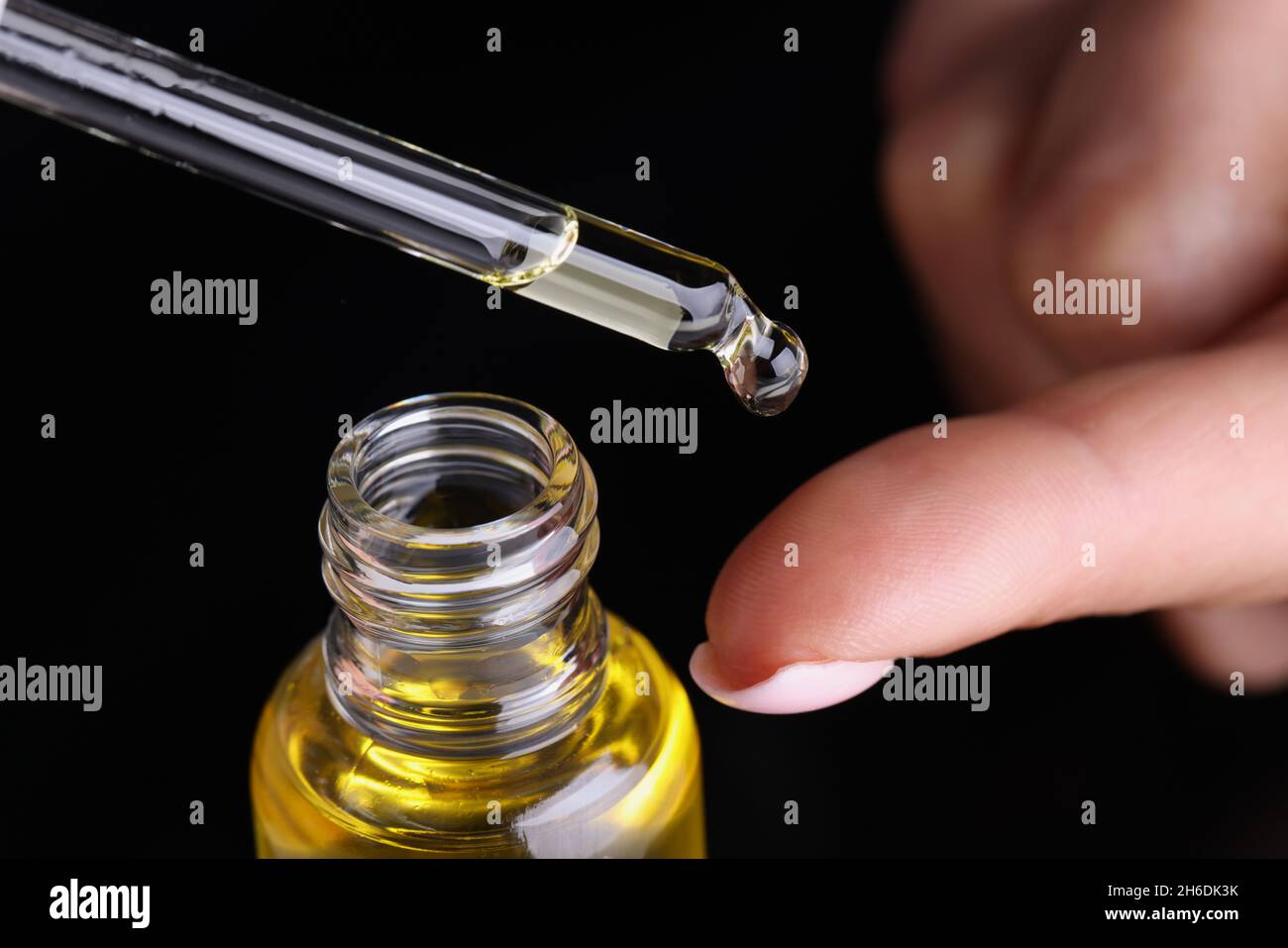 Person dripping drop of extract oil on finger with eyedropper Stock ...