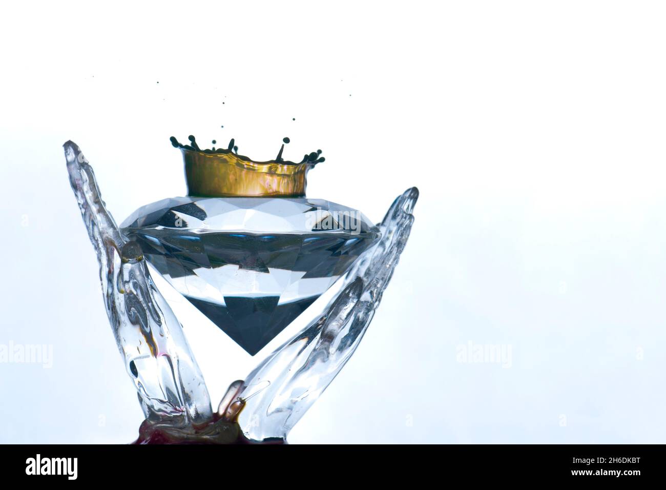 High-speed flash photograph golden liquid droplet on a Diamond held by ...
