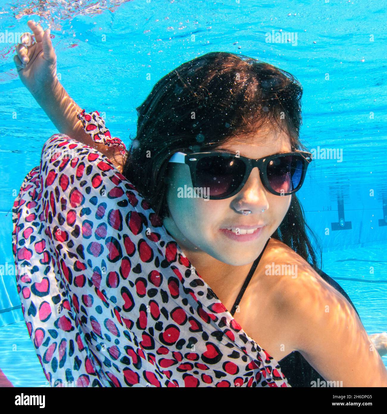A dressed 12 year old female teen free diving underwater in a swimming ...
