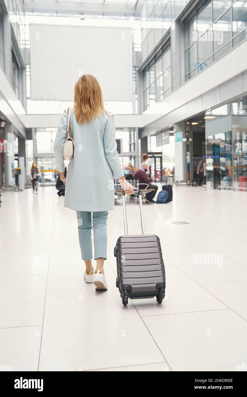 Female passenger pulling luggage along airport terminal Stock Photo - Alamy