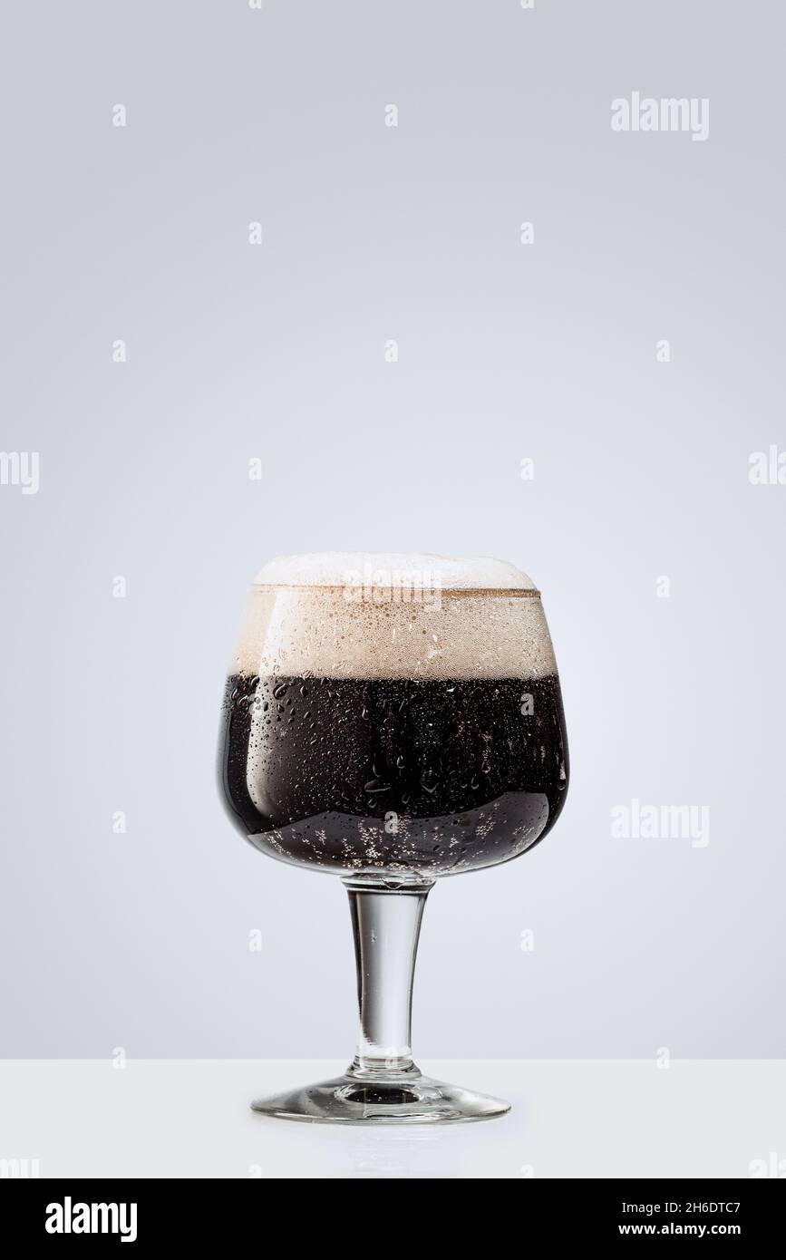 Glass of dark foamy beer isolated over gray background. Concept of ...