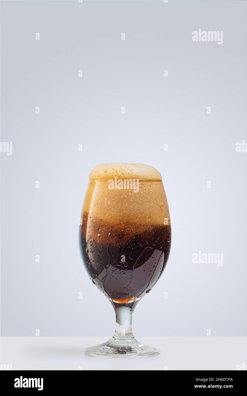 Glass of dark foamy beer isolated over gray background. Concept of ...