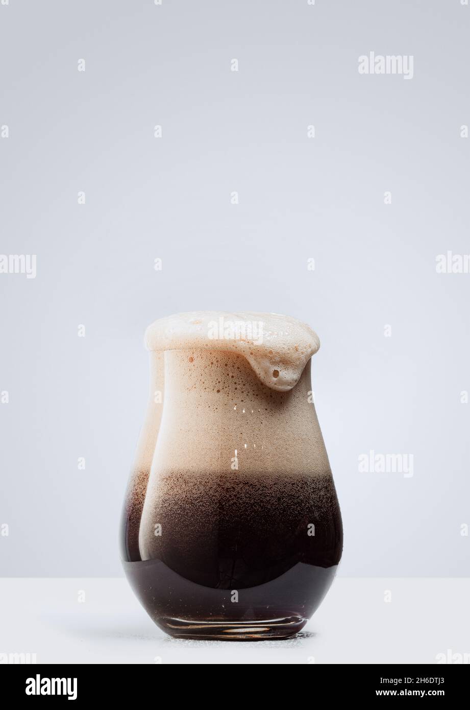 Glass of dark foamy beer isolated over gray background. Concept of ...