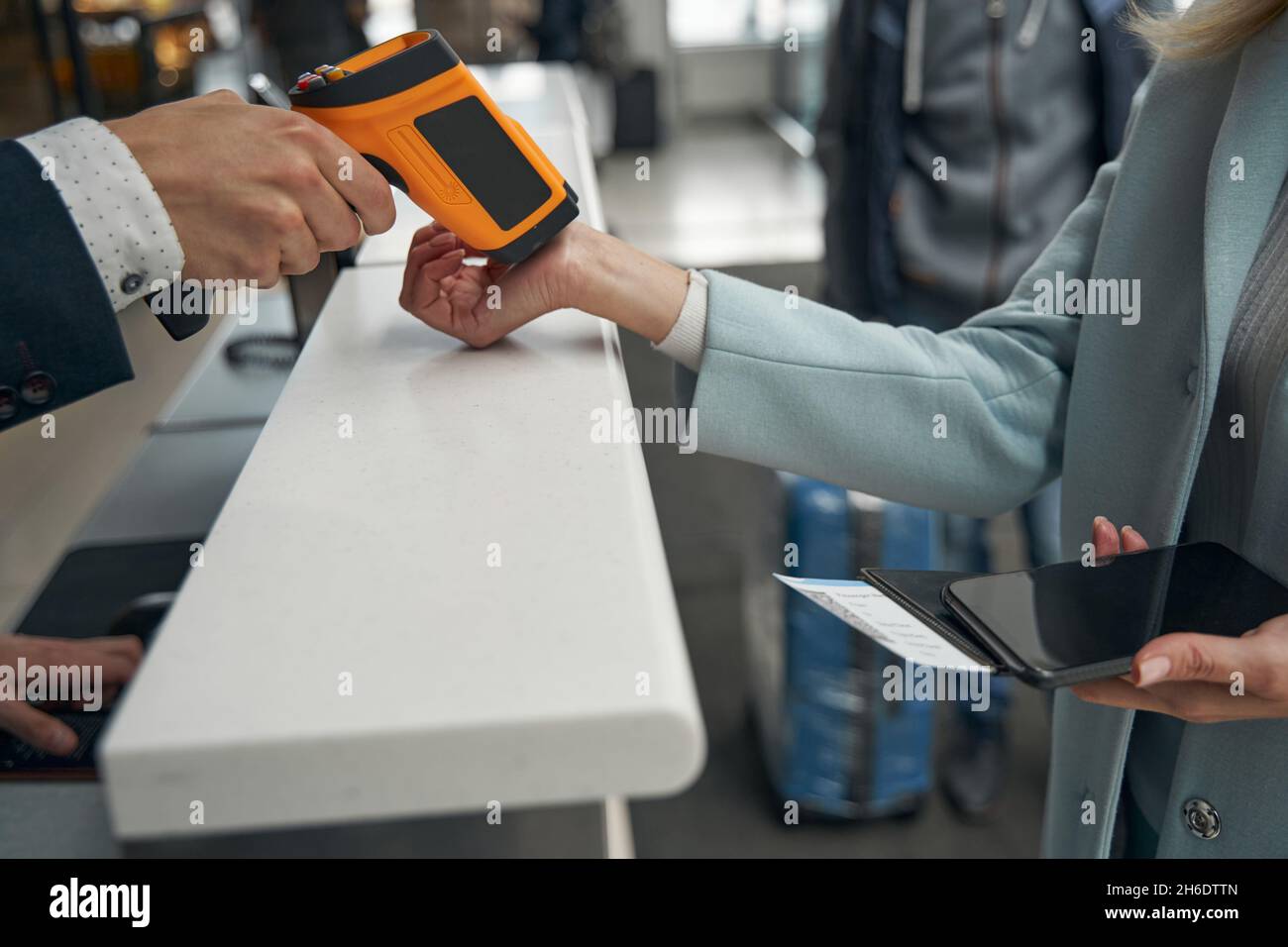 Airport worker measuring passenger temperature with non-contact digital ...
