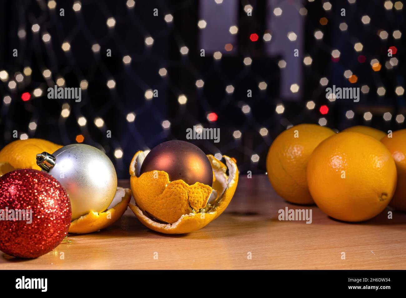 table with oranges and Christmas balls on a background of bokeh lights, xmas ball in orange peel ...