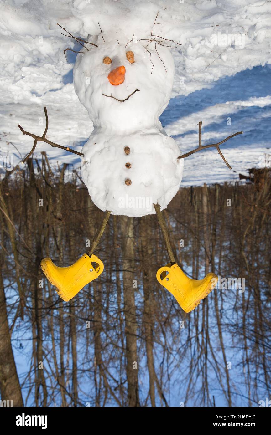 cheerful funny snowman in yellow boots stands upside down in a snowy ...