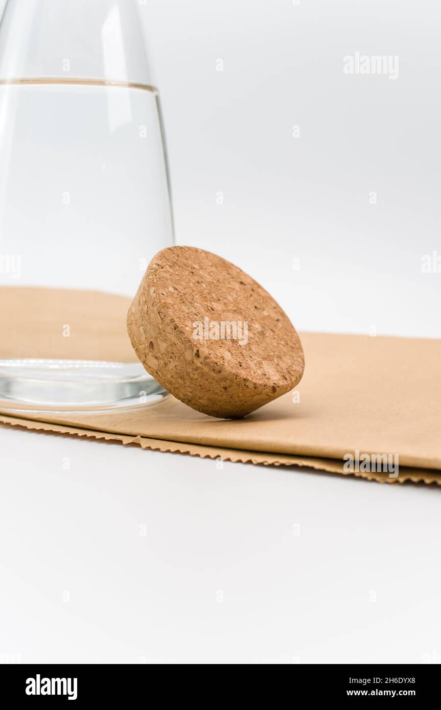 glass carafe with fresh water and cork lid on a white and brown paper ...